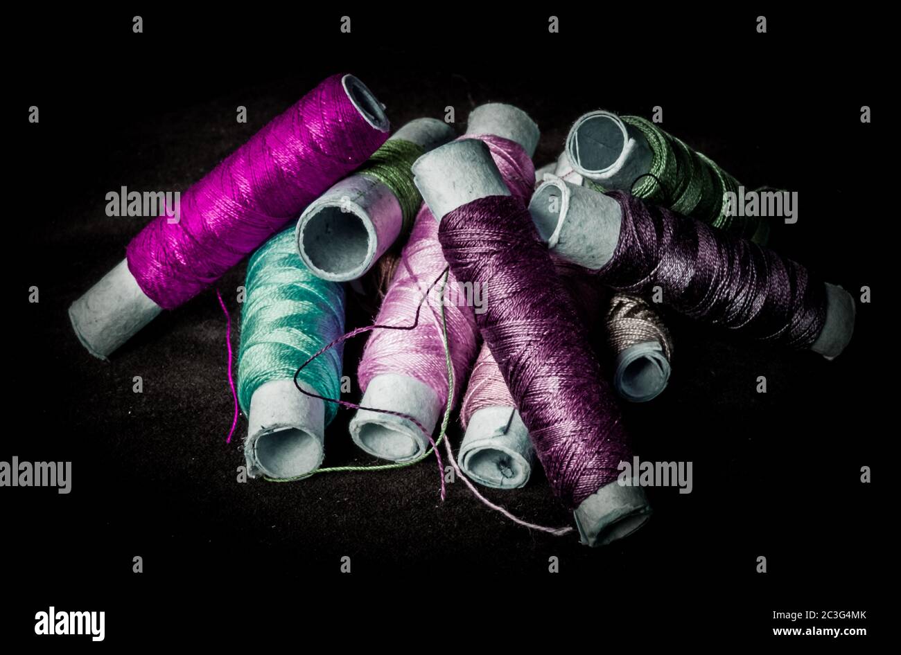 Pile of used colorful spools of thread tailoring, on black background ...