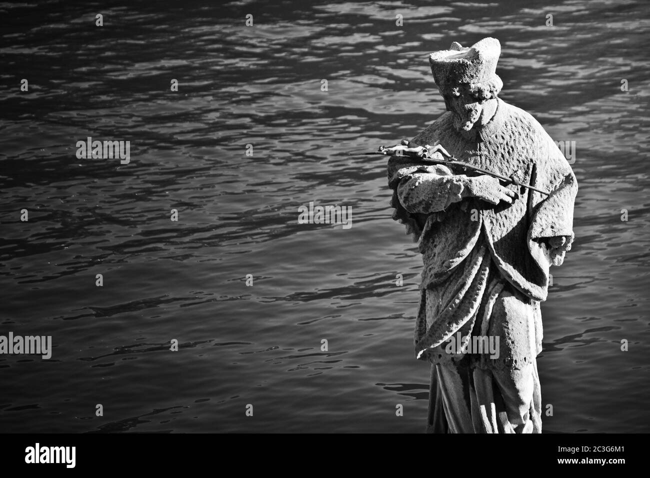 Grayscale shot of a male statue carrying the cross near the sea Stock ...