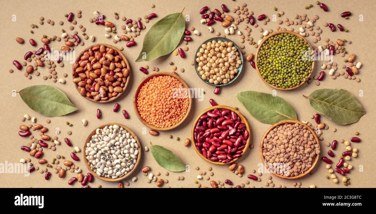 Legumes assortment, overhead panoramic shot on a brown background ...