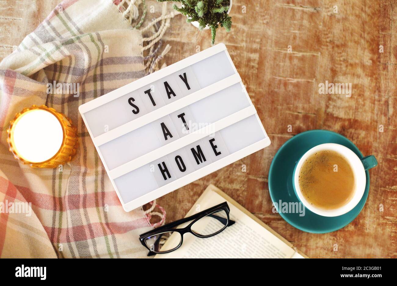 Board with Stay At Home writing, cup of coffee, burning candle and ...