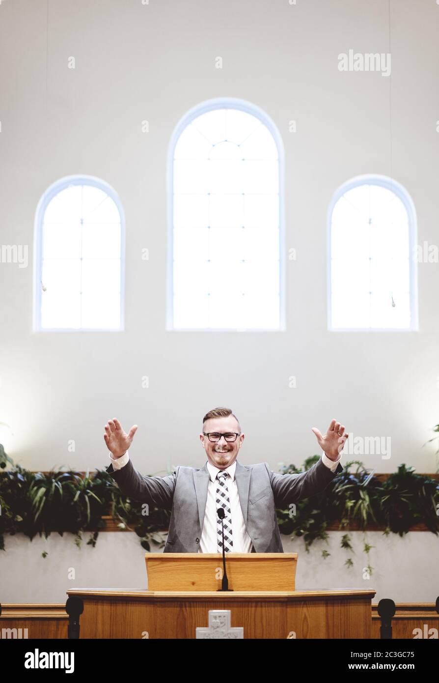 Vertical shot of a male in a suit preaching words of the Holy Bible at ...