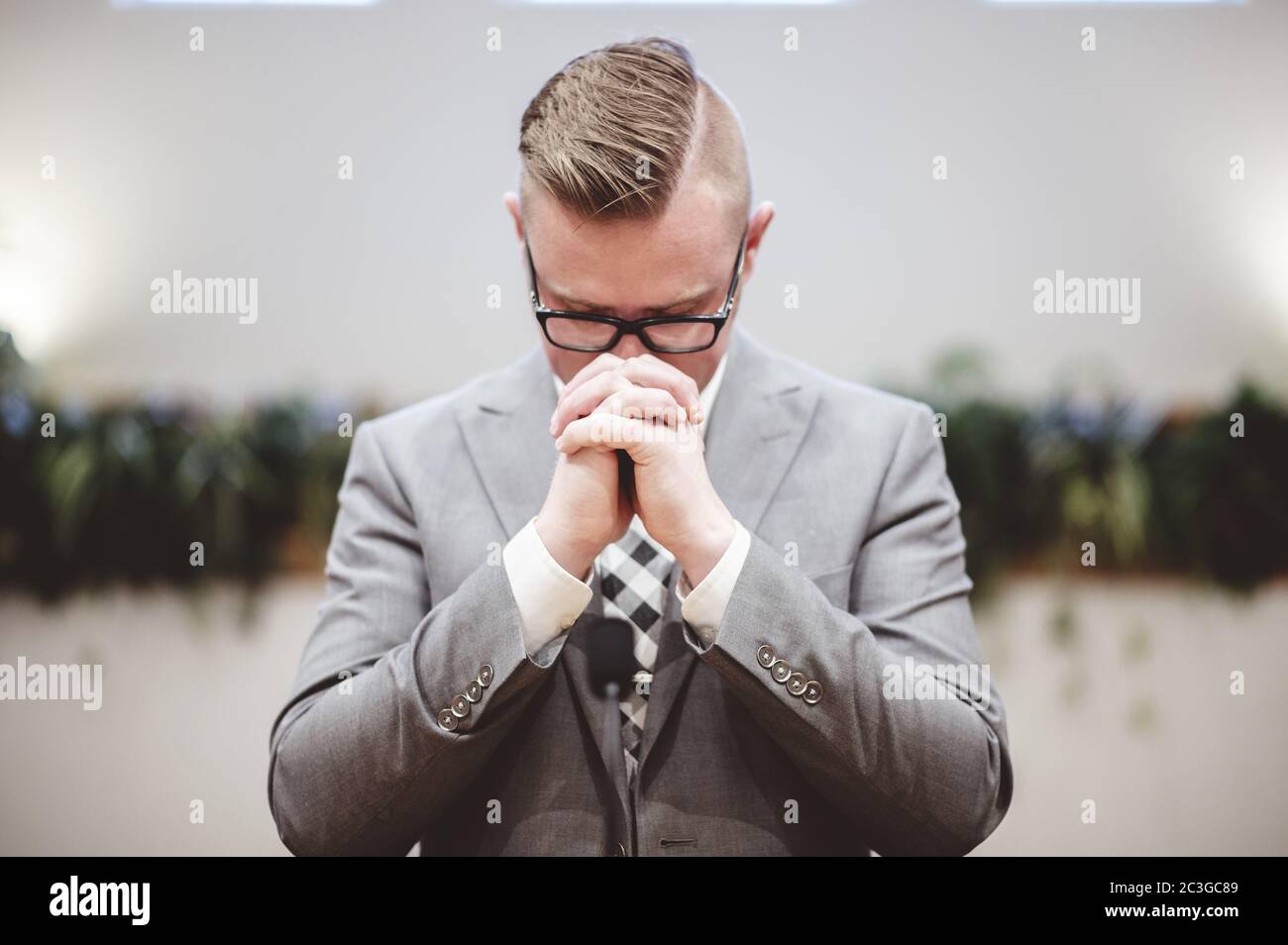 Male in a grey suit preaching words of the Holy Bible at the altar of a ...