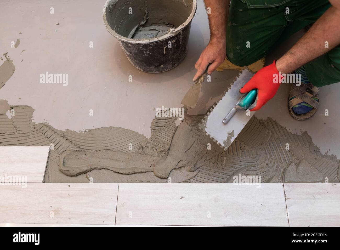 Professional construction worker laying ceramic tiles on the floor in ...