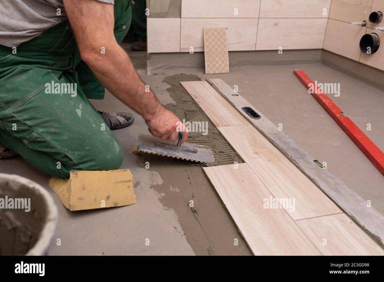 Professional construction worker laying ceramic tiles on the floor in ...