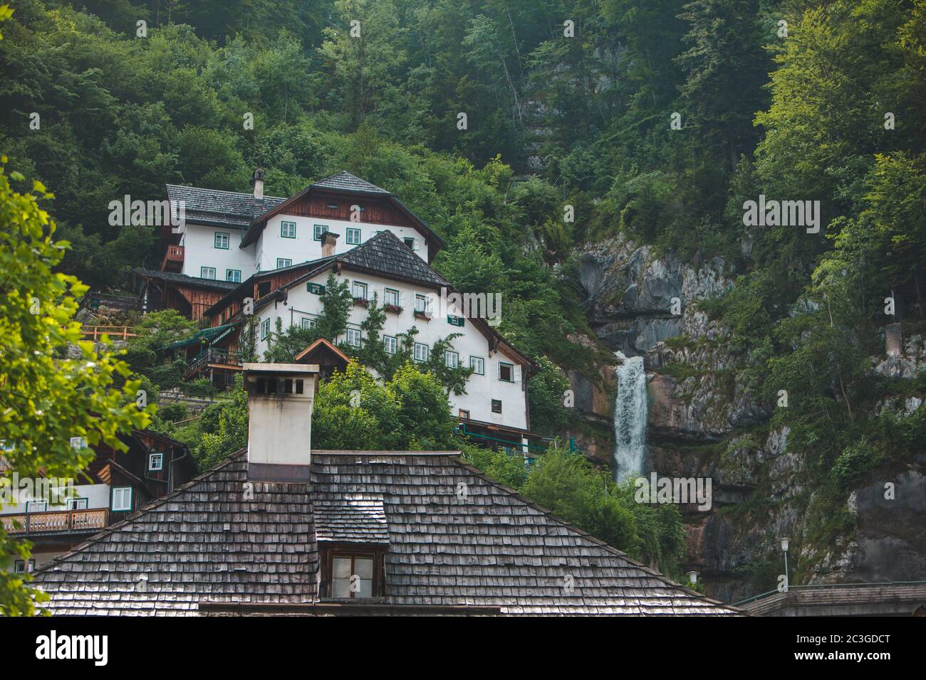 view of hallstatt buildings waterfall on background Stock Photo - Alamy