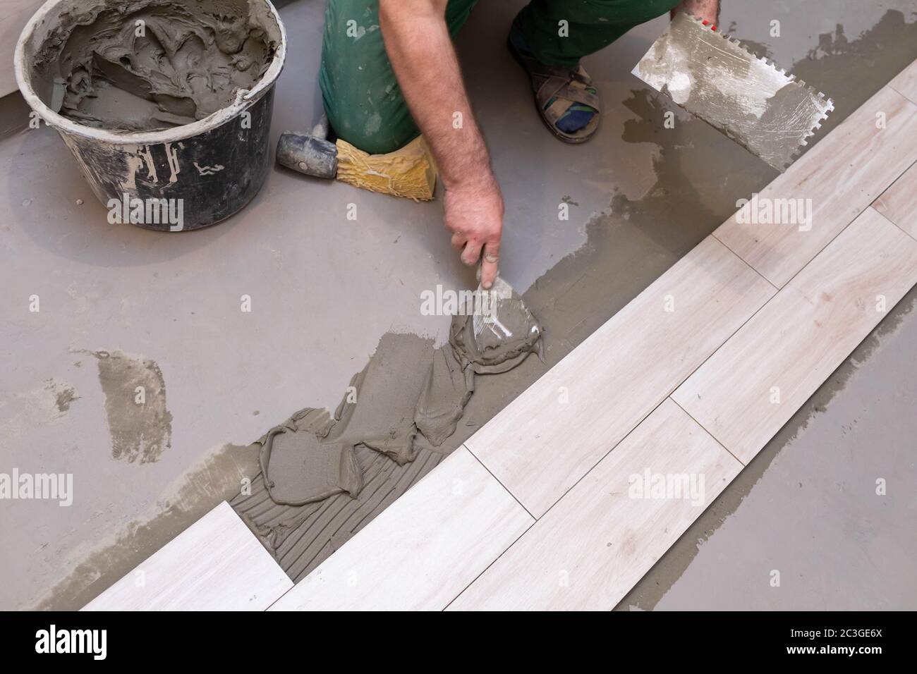 Professional construction worker laying ceramic tiles on the floor in ...