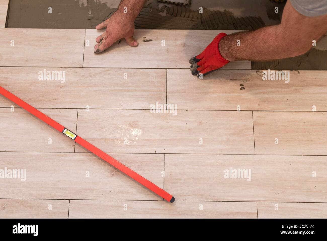He presses the ceramic tile against the floor with his hand. Protective ...