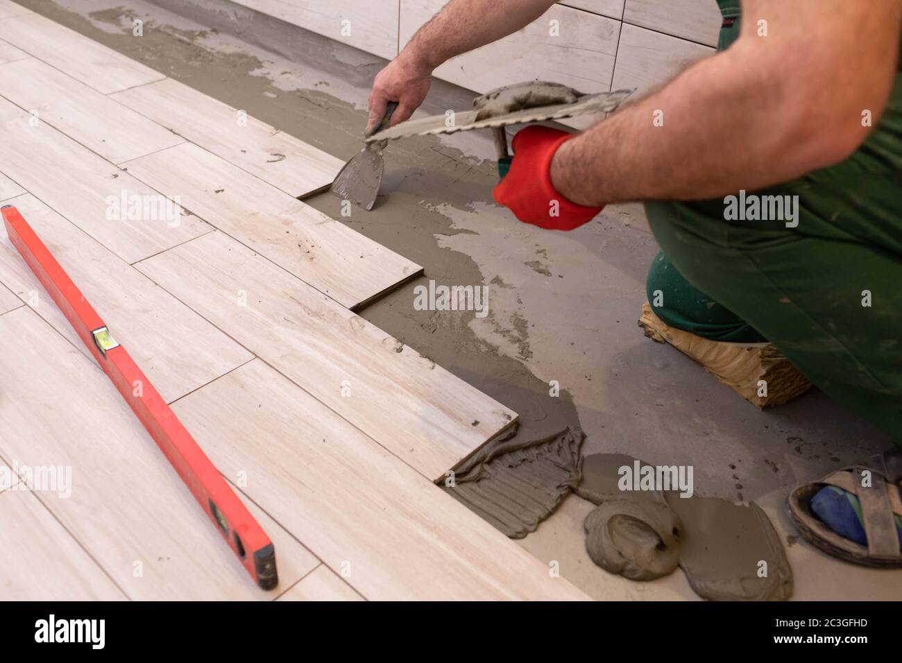 Professional construction worker laying ceramic tiles on the floor in ...