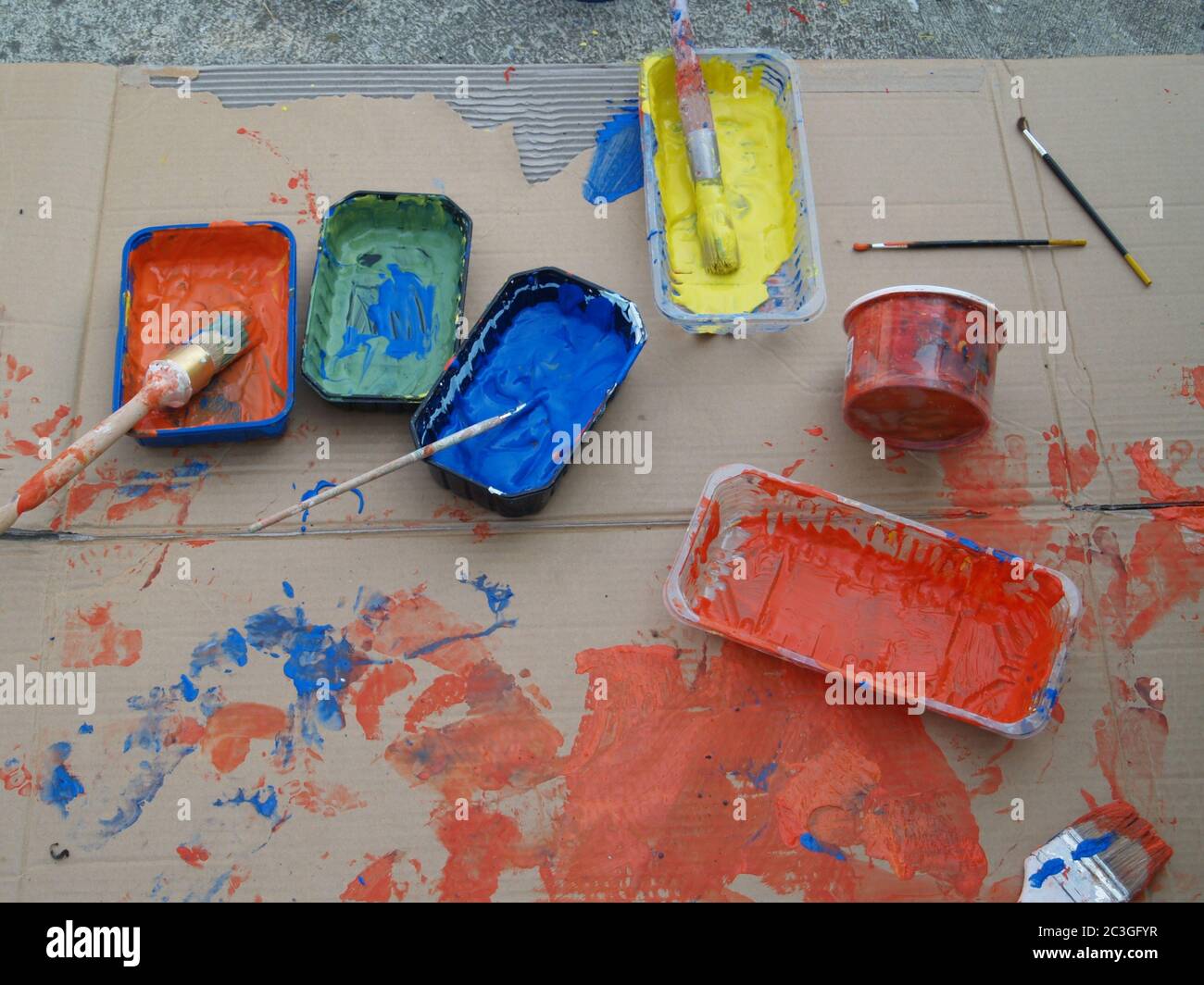 High angle shot of multicolor paint containers with paintbrushes on the ...