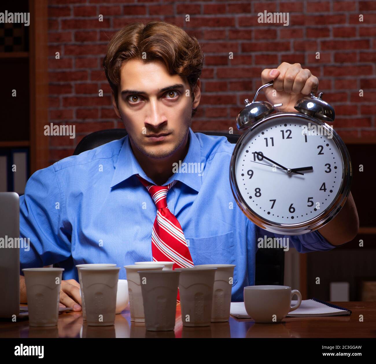Young employee drinking coffee working at night shift Stock Photo - Alamy