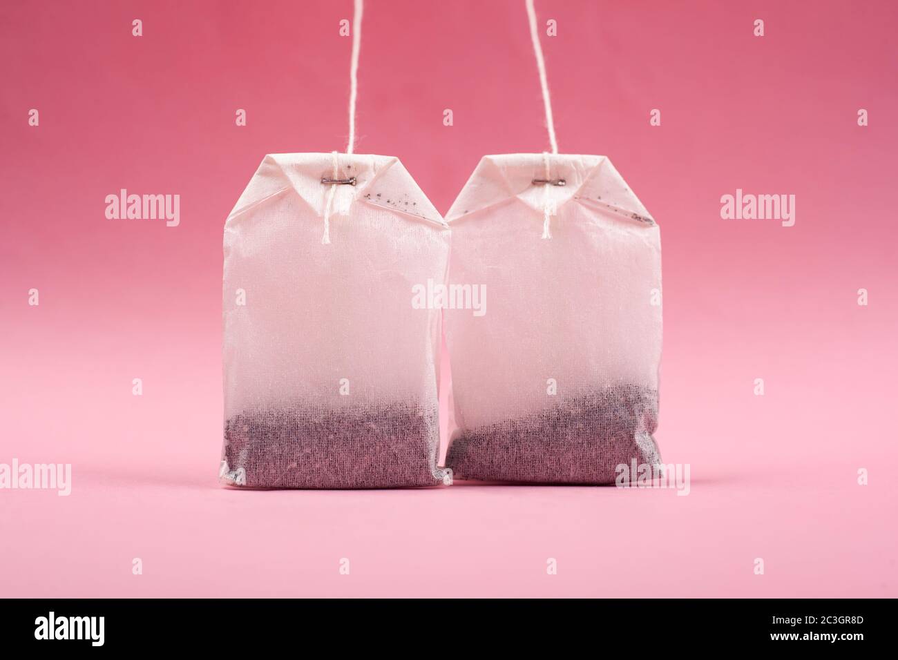 two tea bags on a pink background Stock Photo - Alamy