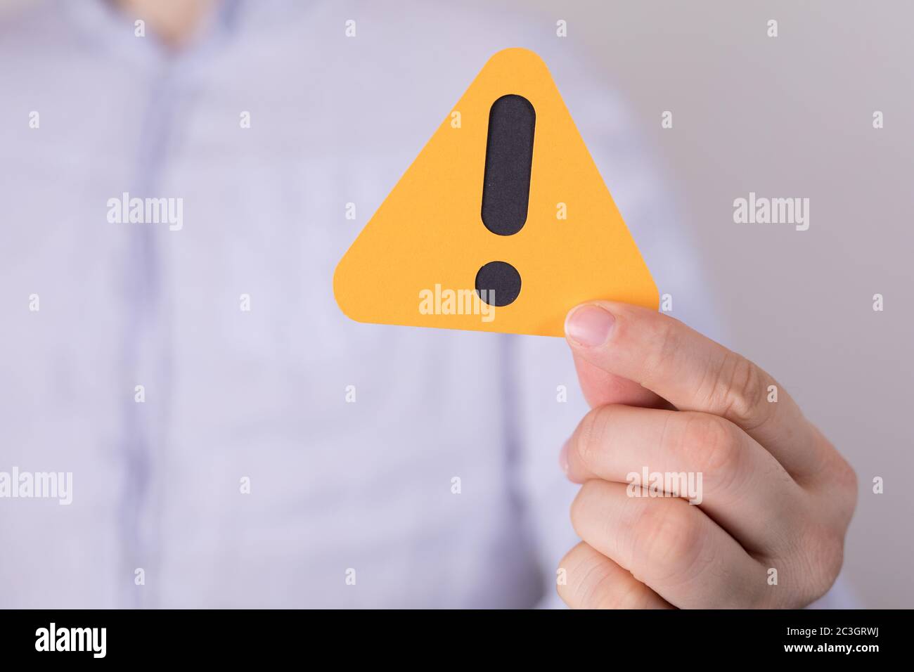 Man holding a yellow triangular warning sign Stock Photo - Alamy