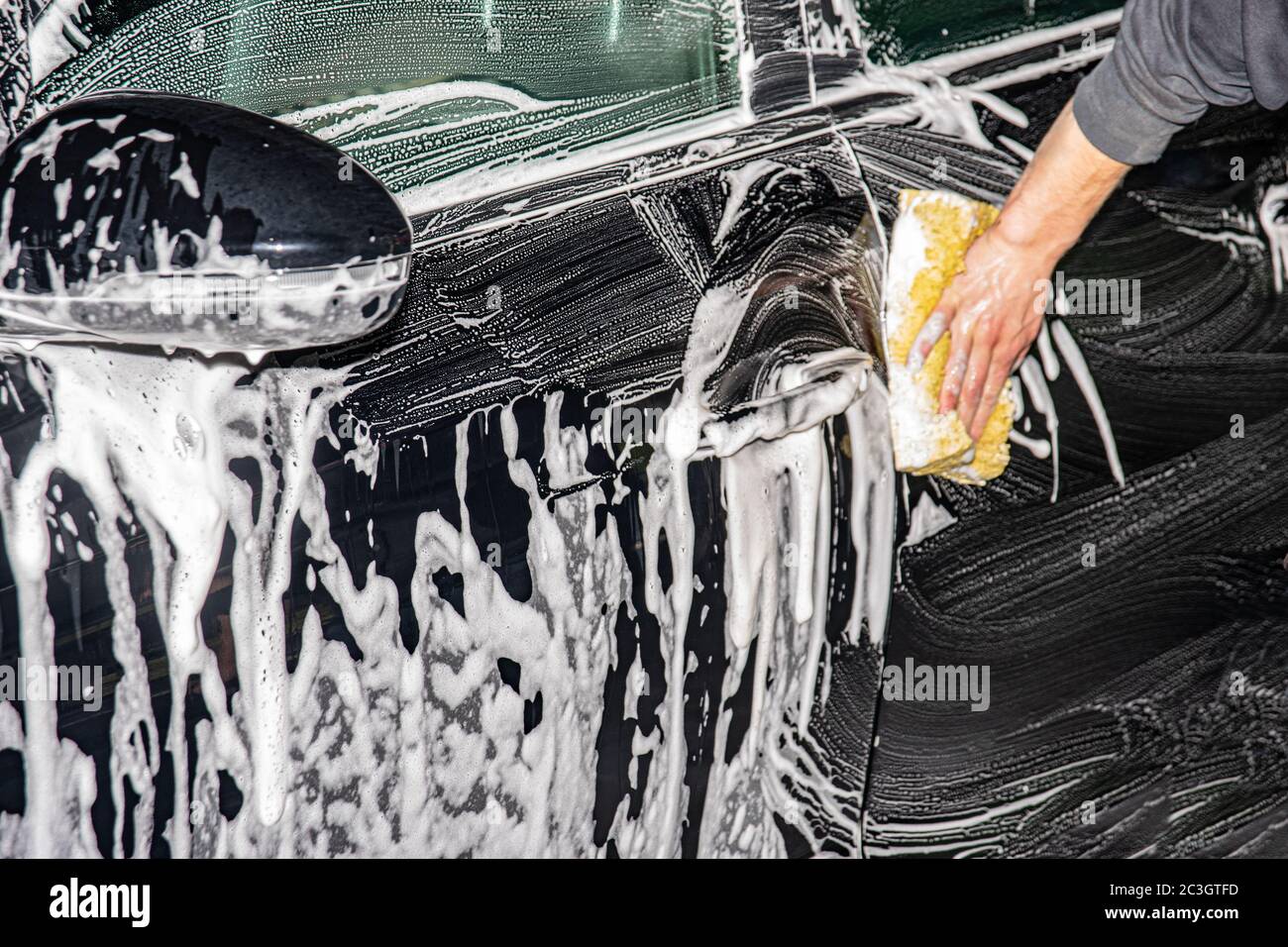 Closeup of the front side of a modern black car. rubbing and cleaning ...