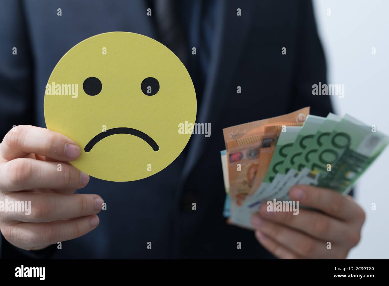 Man holding money and a sad smiley face Stock Photo - Alamy