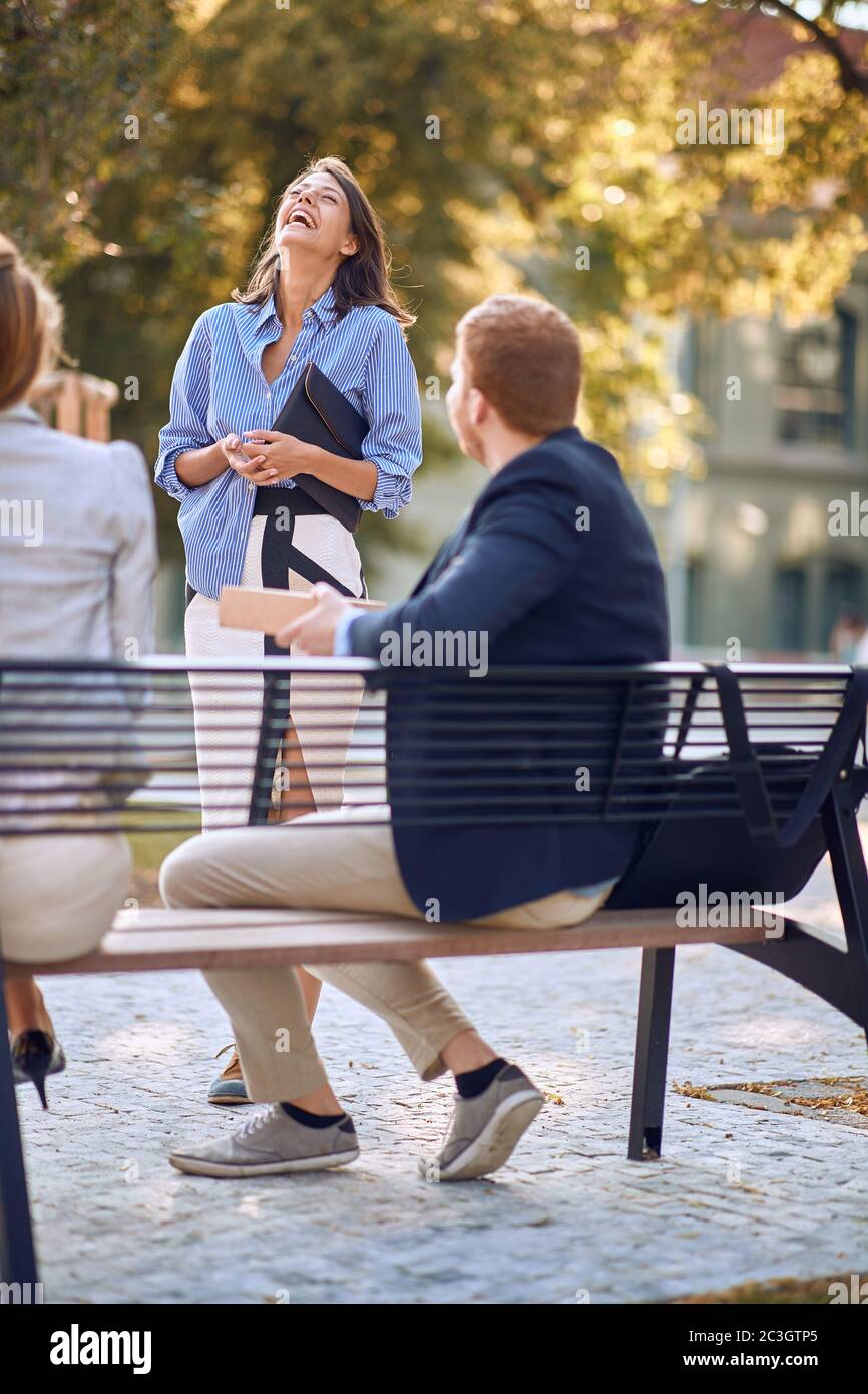young caucasian businesswoman laughing with colleagues on break in park ...