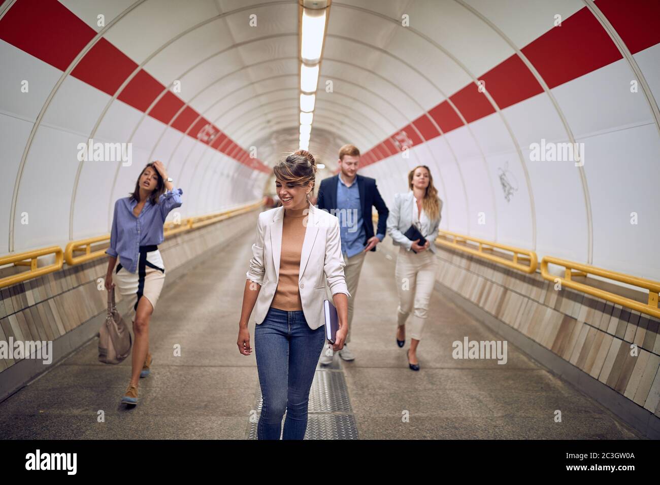 group of young people walking through pedestrian subway in a hurry ...