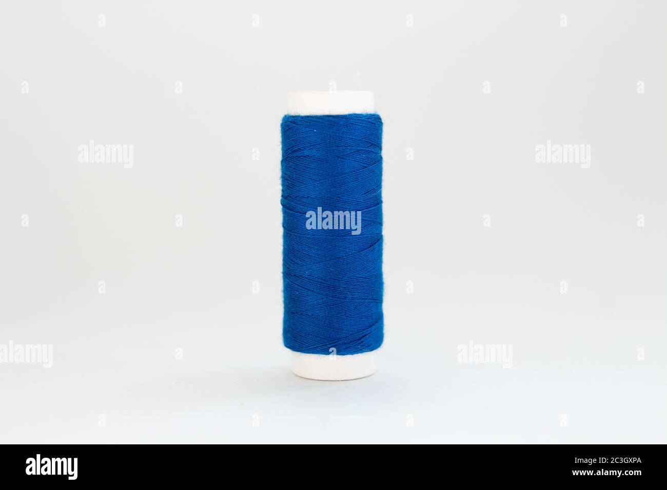 spool of blue thread on white background Stock Photo - Alamy