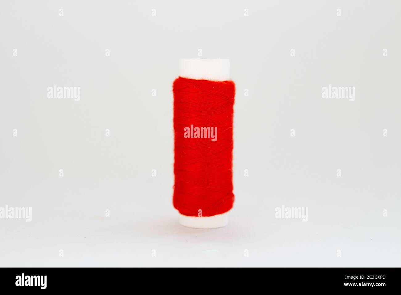 spool of red thread on a white background Stock Photo - Alamy