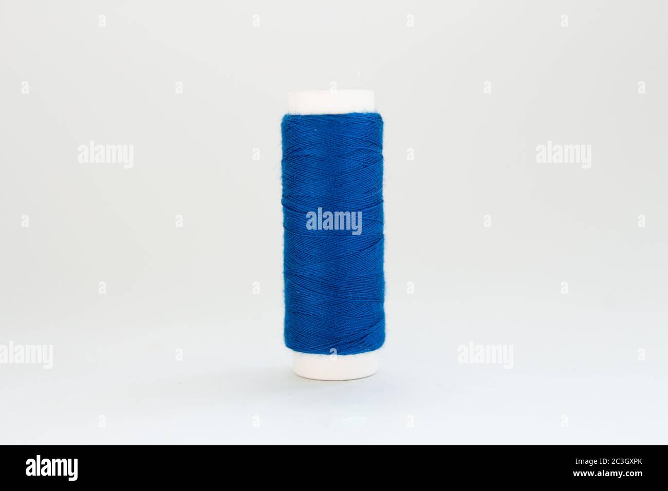 spool of blue thread on white background Stock Photo - Alamy