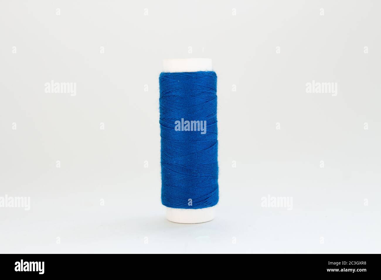 spool of blue thread on white background Stock Photo - Alamy
