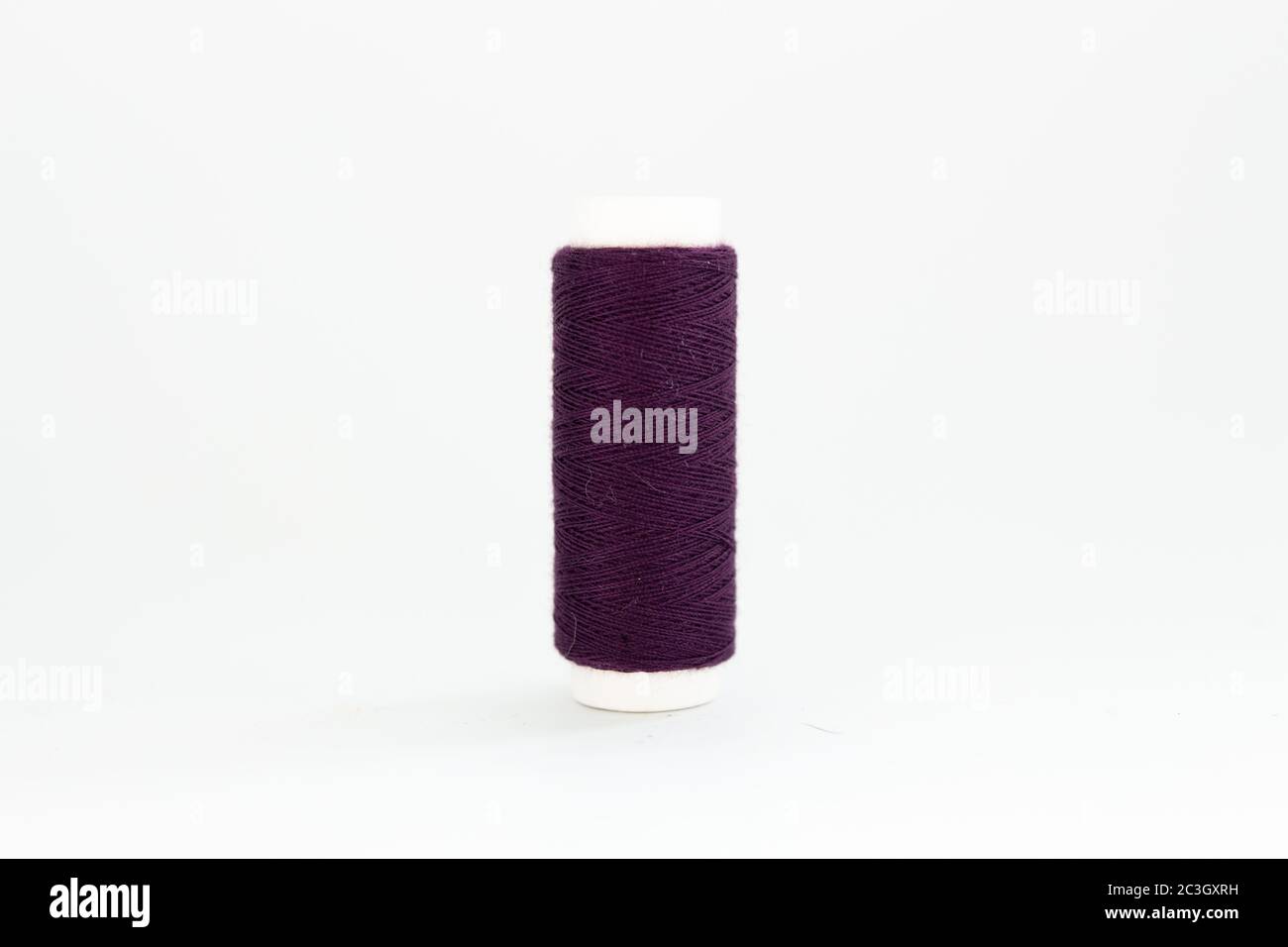 spool of purple thread on white background Stock Photo - Alamy