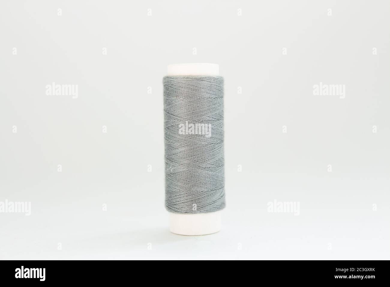 spool of gray thread on white background Stock Photo - Alamy