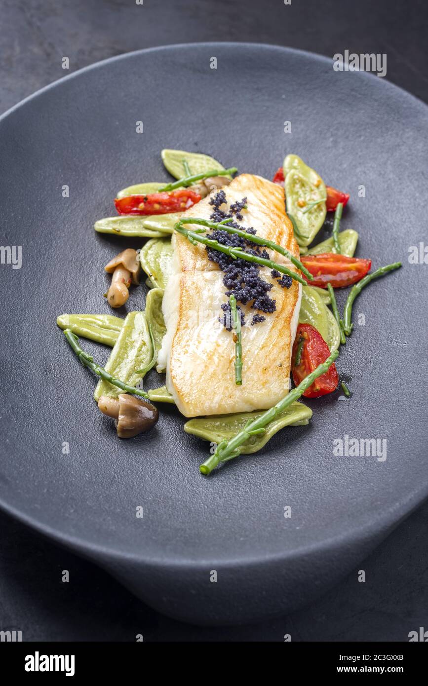 Gourmet fried Italian sea bass fish filet with spinach pasta Stock ...