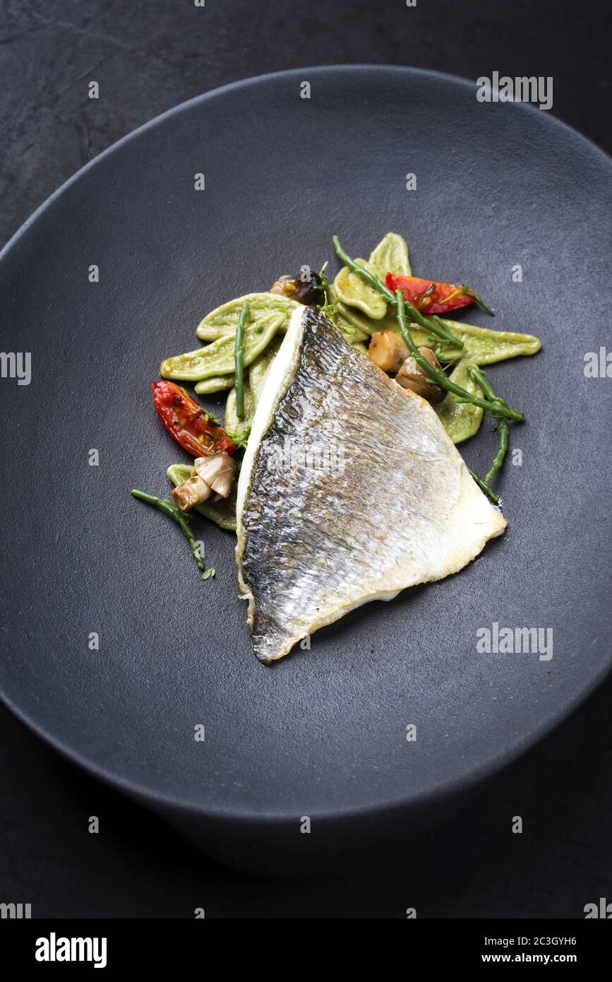 Gourmet fried Italian gilthead fish filet with spinach pasta Stock ...