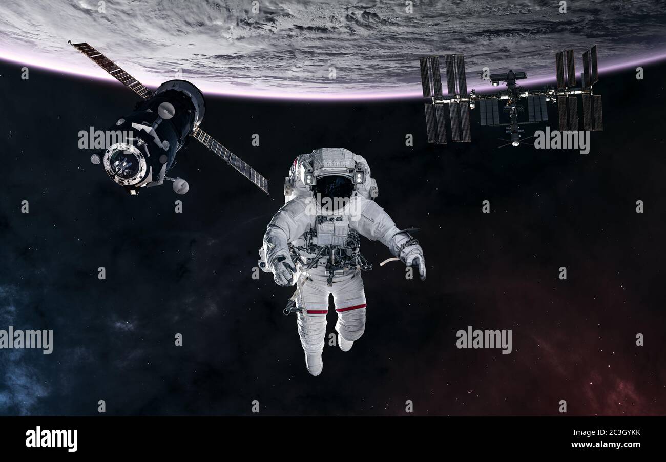 Astronaut and space stations in orbit of planet in light of red and ...