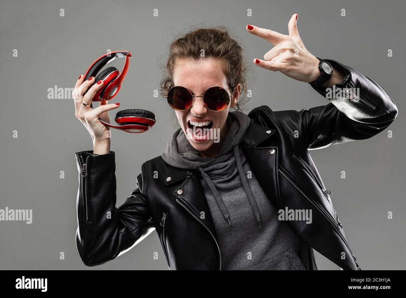 A young girl with rough facial features in a black jacket listens to ...