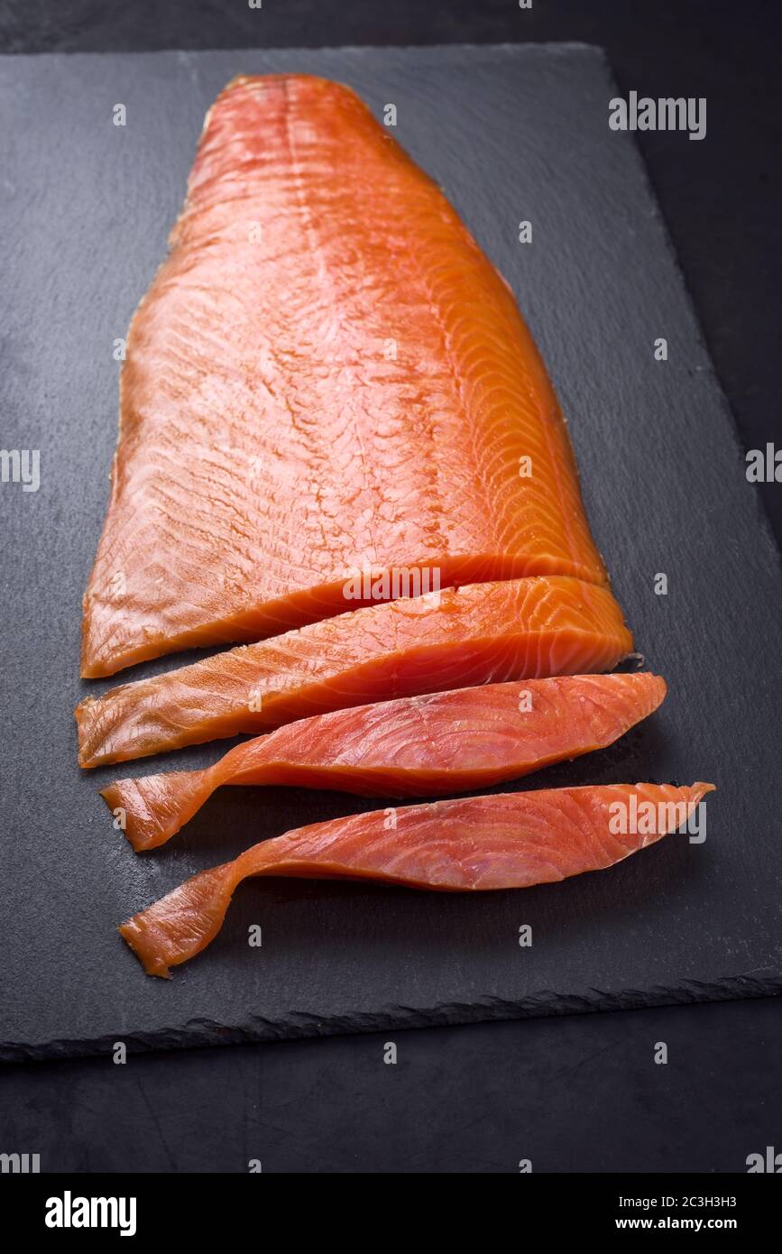 Traditional fresh graved salmon filet offered as closeup on a black ...