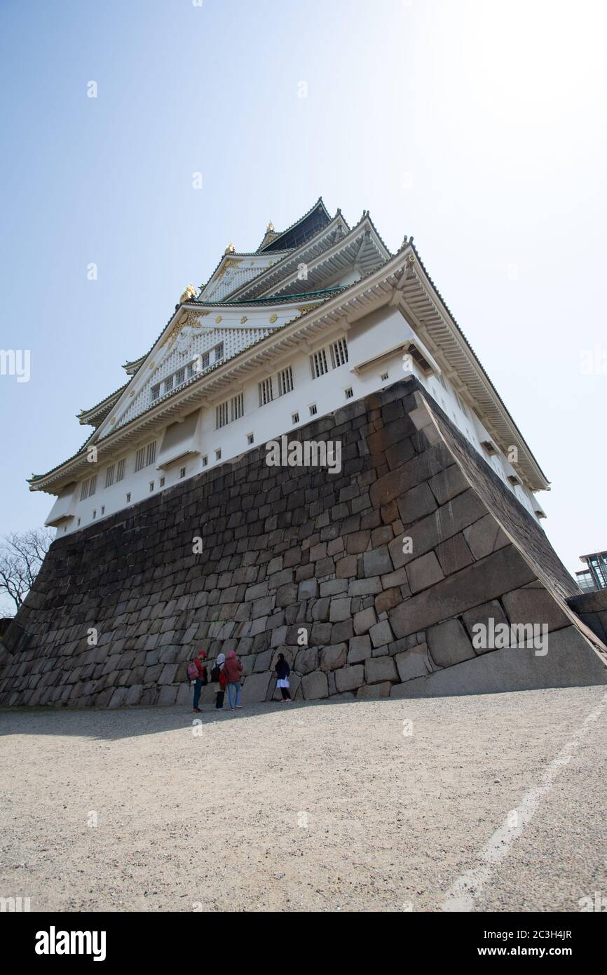 Low angle shot of the Osaka Castle and the stone wall base against a ...