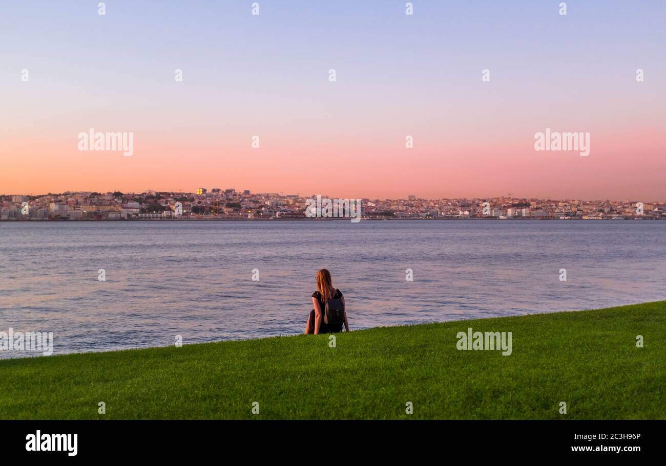 Tourist girl with a backpack sitting on a grass in Jardim do Rio park ...