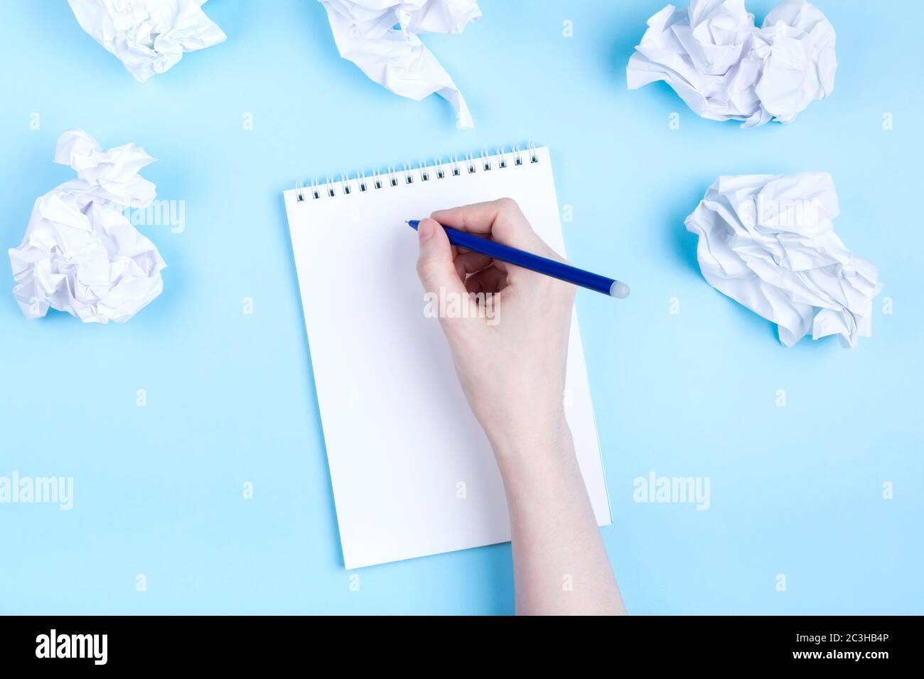 Woman writes in notebook around crumpled paper, blue background ...