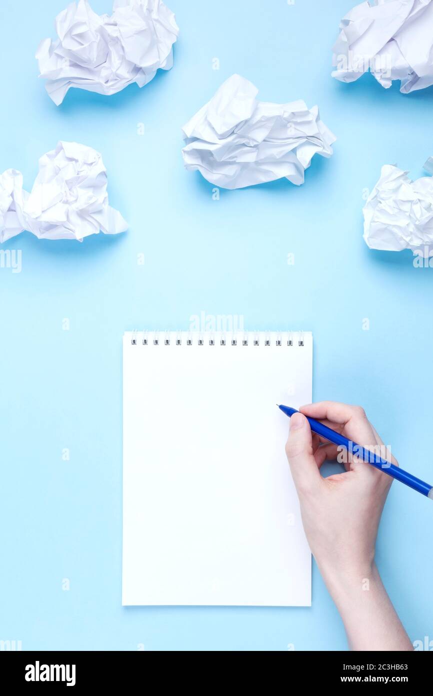 Woman writes in notebook around crumpled paper in the form of clouds on ...