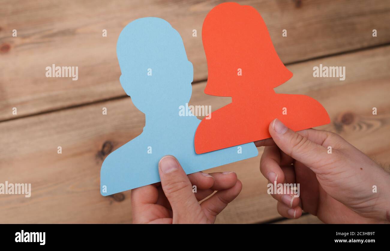 Man holding a blue and red male and female icons on a wooden background ...