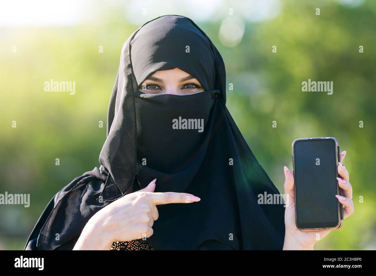 Islamic muslim woman holds modern mobile phone in her hand. Cellular ...