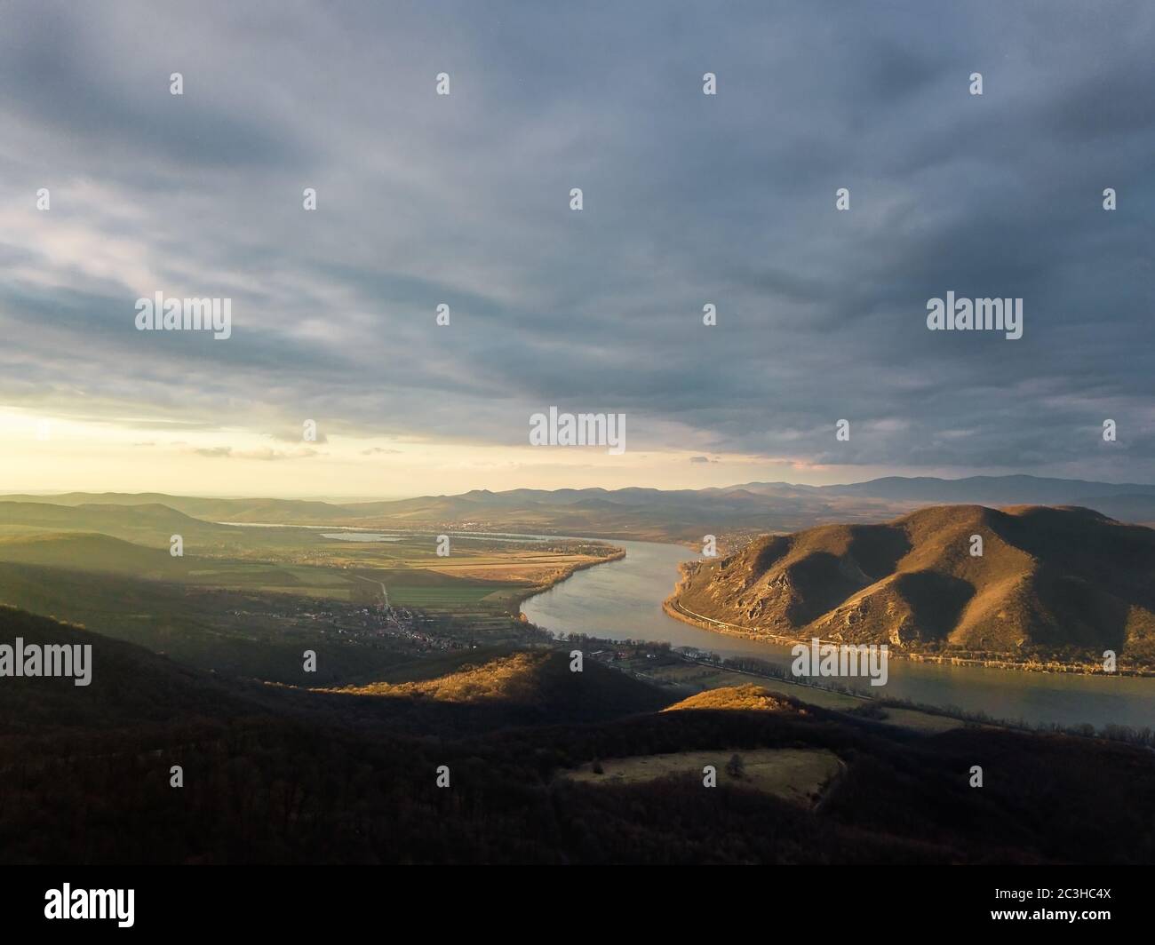 Mesmerizing scene of a river between forest and hill under the cloudy ...