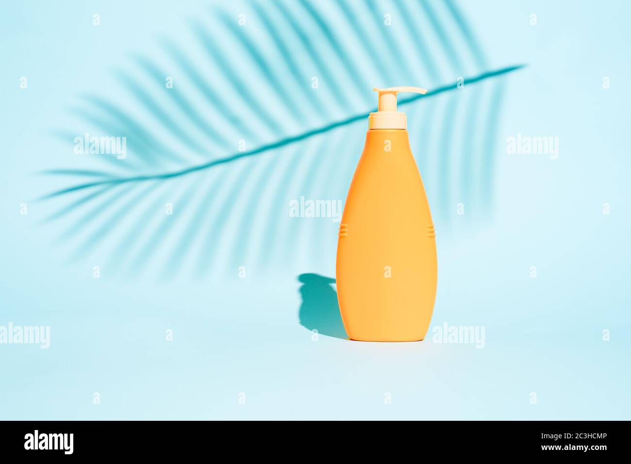 Orange container for lotion without label on blue background with leaf ...