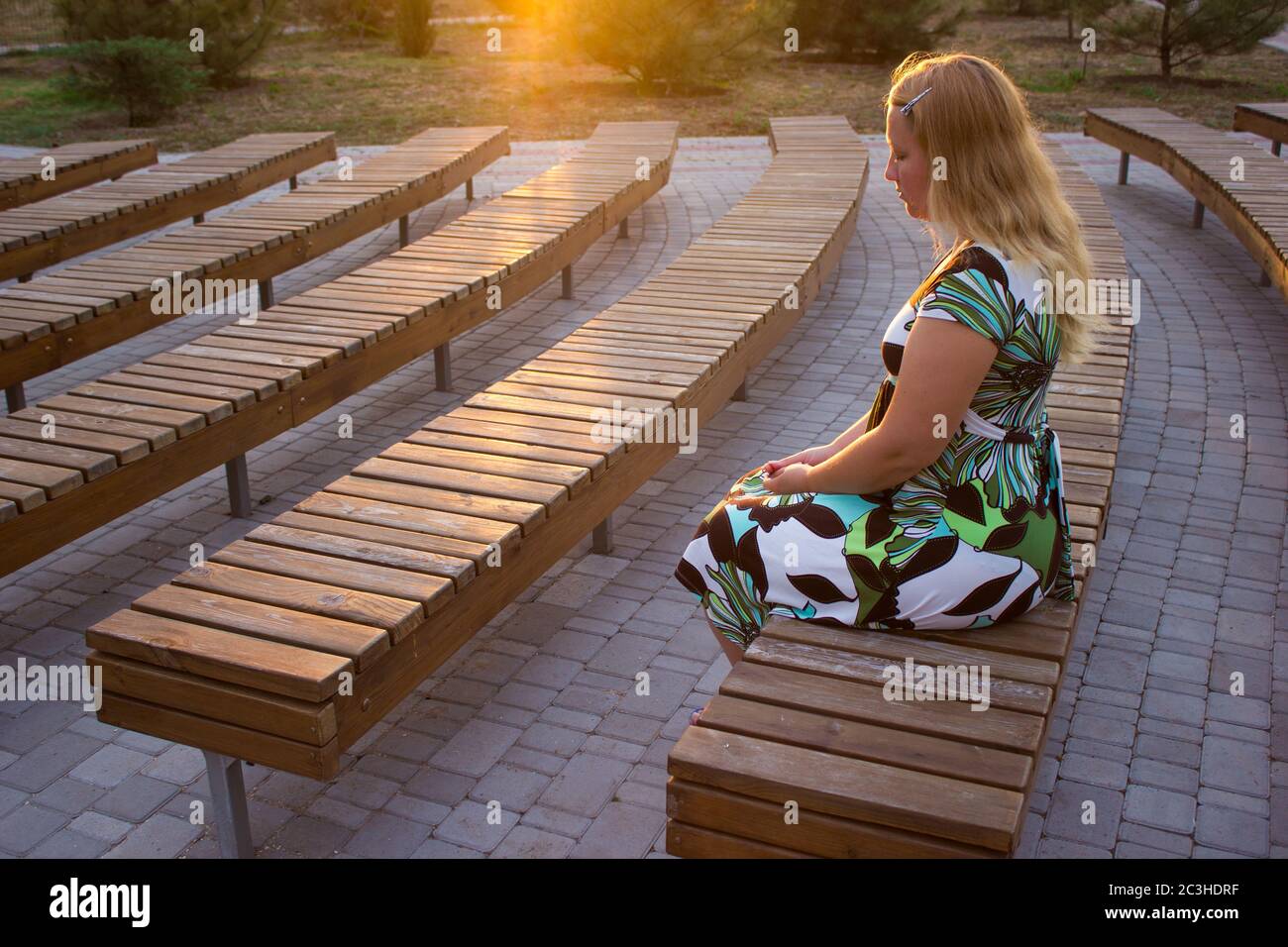 The girl is sitting alone in her back among the many benches of the ...