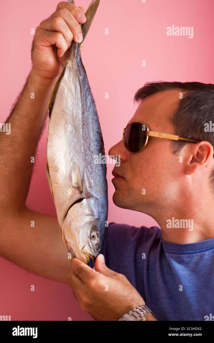 Young man with a fish in his hands, wants to eat sniffing - salted tuna ...
