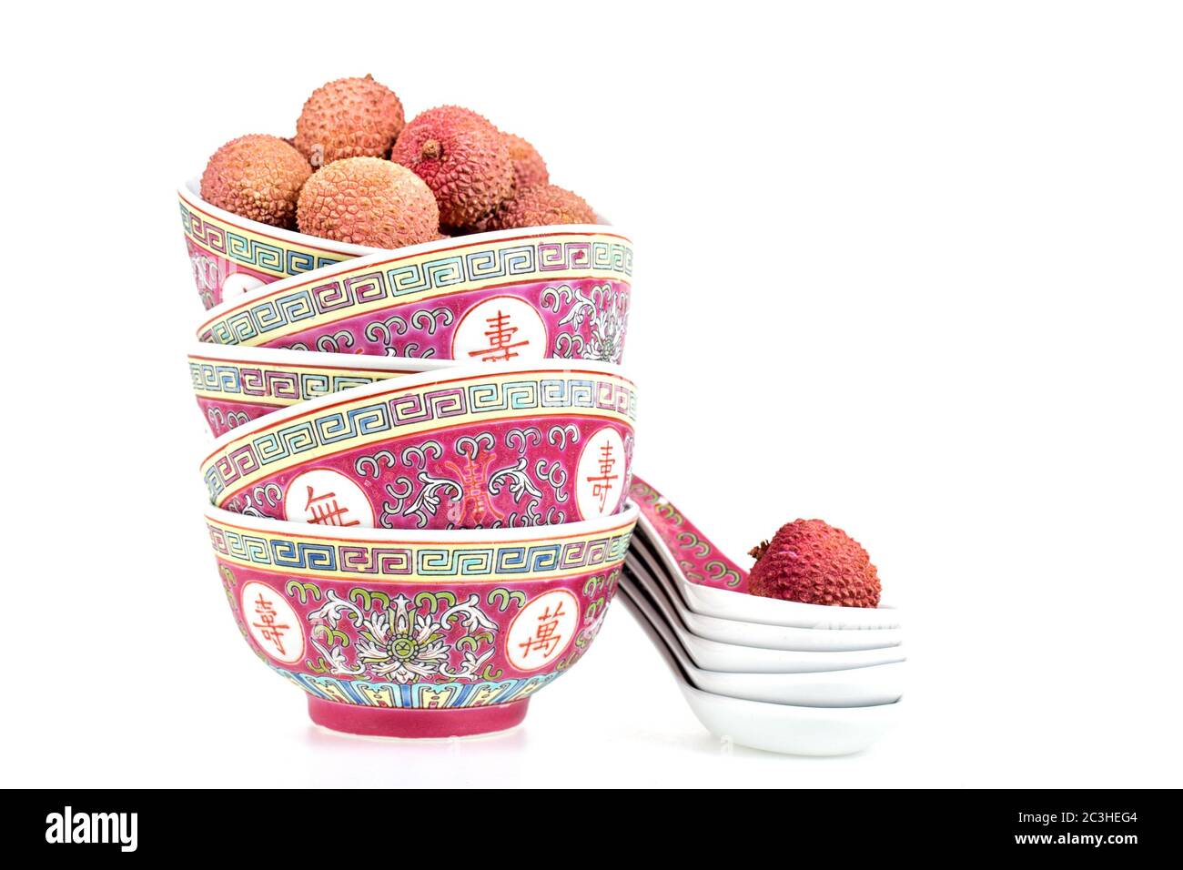 Fresh lychees in a stack of traditional Chinese bowls with spoons, over ...
