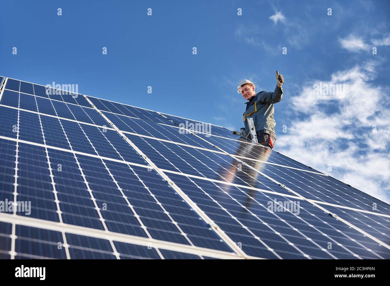 Cheerful male worker giving thumbs up and smiling while installing blue ...