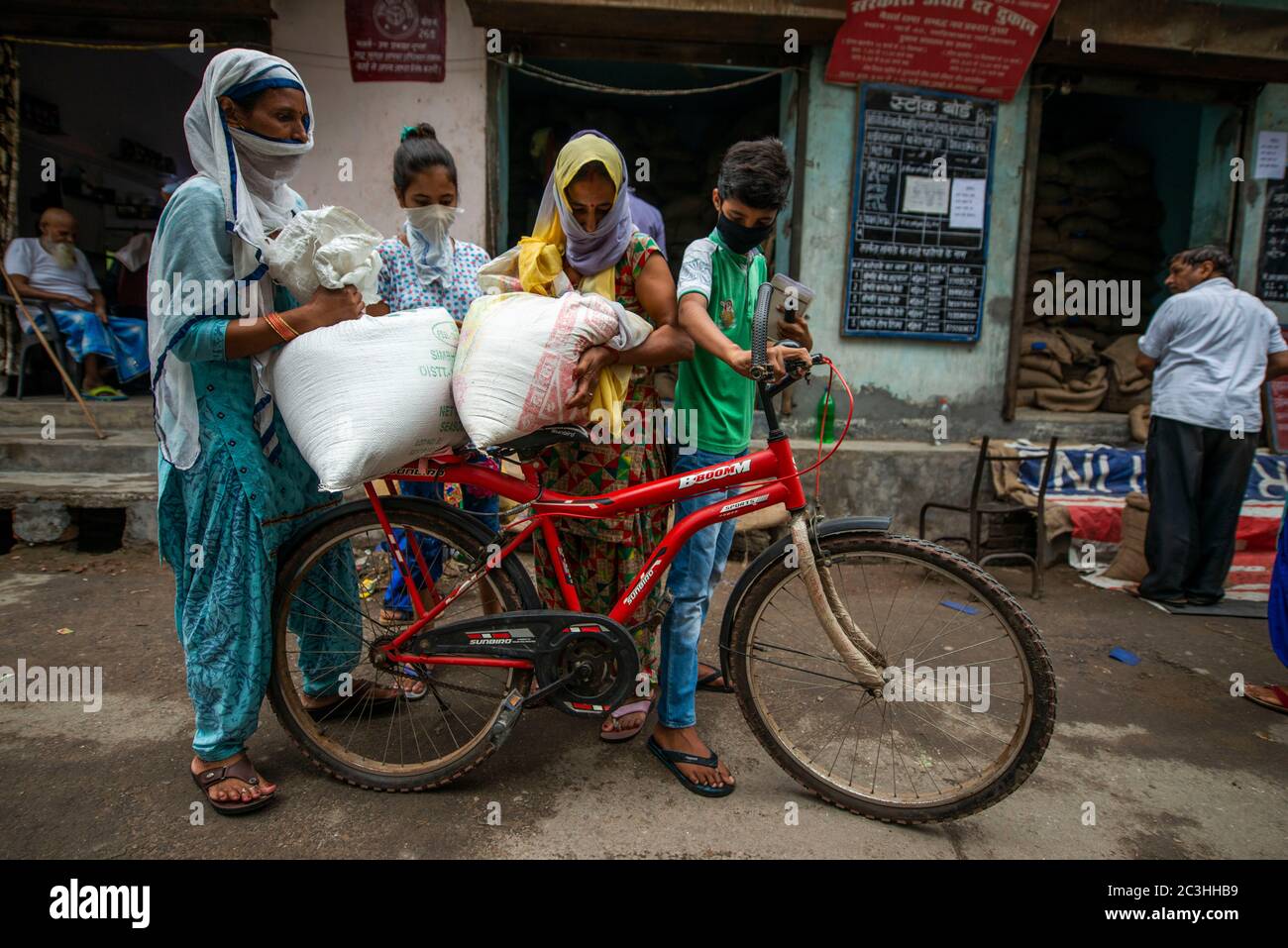 A boy along with his family load two bags full of ration on a bicycle ...