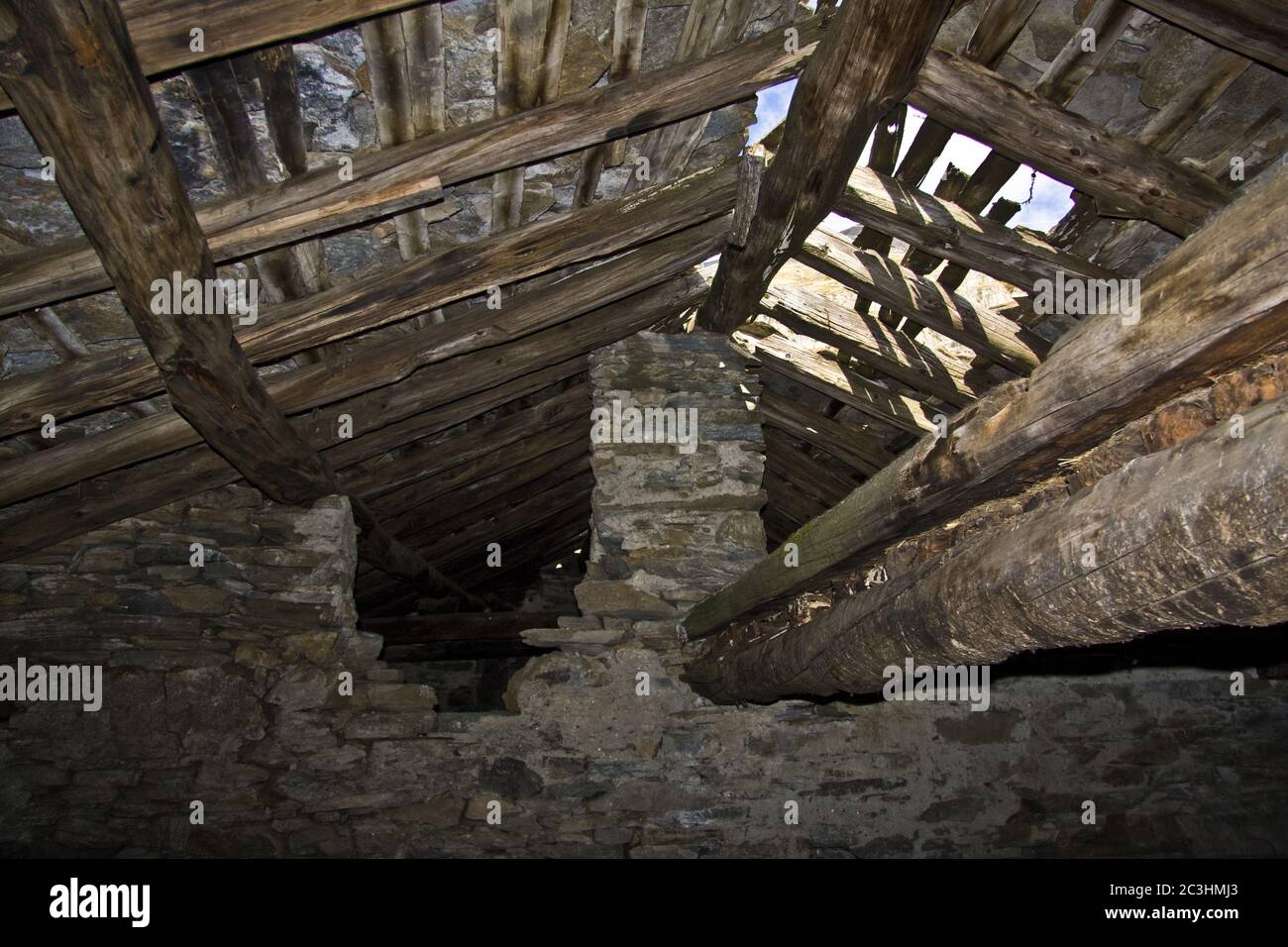 Interior of an old ruined barn with a wooden ceiling under the sunlight ...