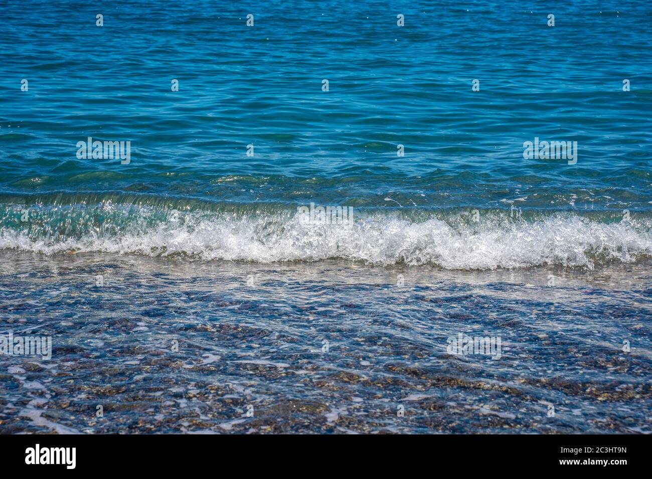 Small sea blue wave reaching a calm beach. Front view close-up Stock ...
