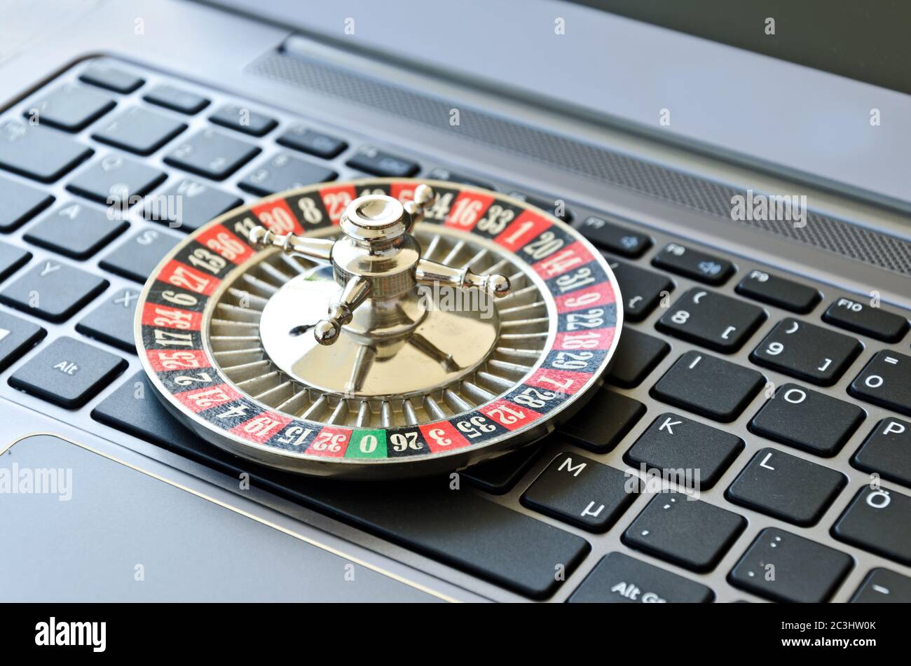 Roulette wheel lying on computer keyboard symbolizing online gambling ...