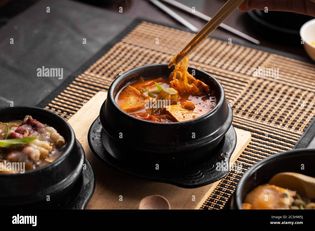 High angle shot of a person eating Chinese food from a black plate with ...