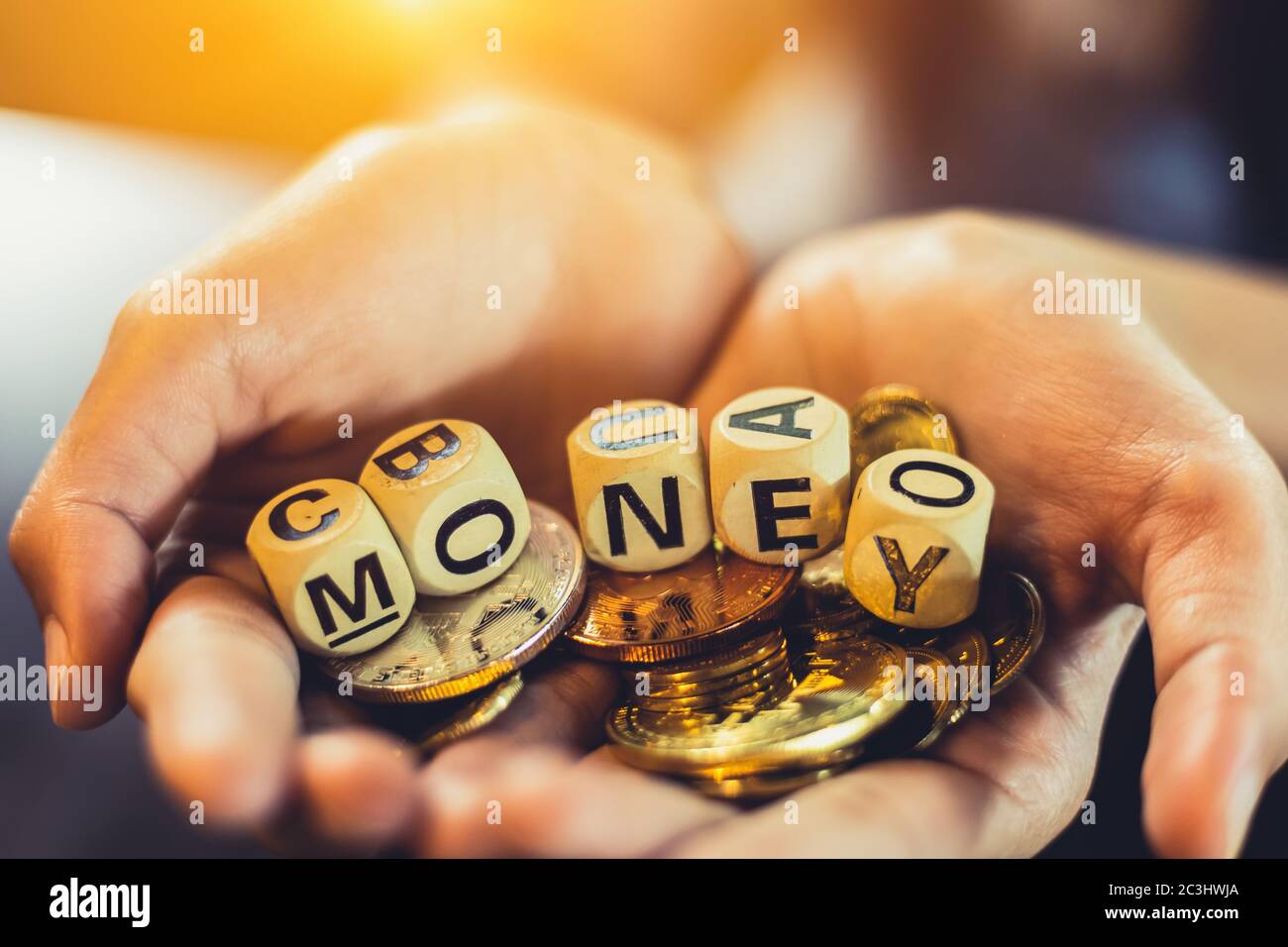 wood cube word "money" on coin in hands Stock Photo - Alamy
