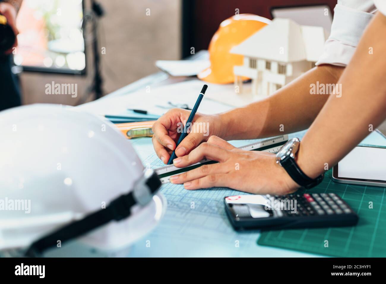 engineers holding a pen pointing to a building and drawing outlay ...